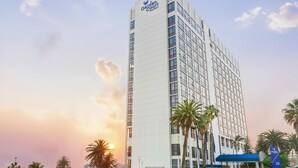 Um edifício de hotel alto e moderno com um destaque para o letreiro 'Garden Court' no topo.