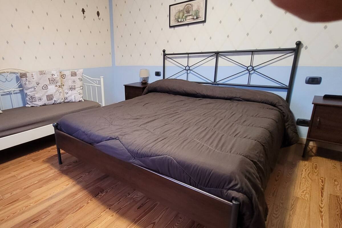 Quarto com cama, mesa de cabeceira, luminária e quadro na parede.
