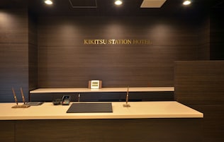 Bancada de recepção no HOTEL KIKITSU STATION com um relógio digital, um telefone e um porta-canetas.