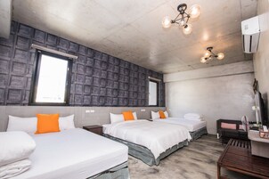 Quarto de hotel com duas camas, uma mesa e uma janela grande.