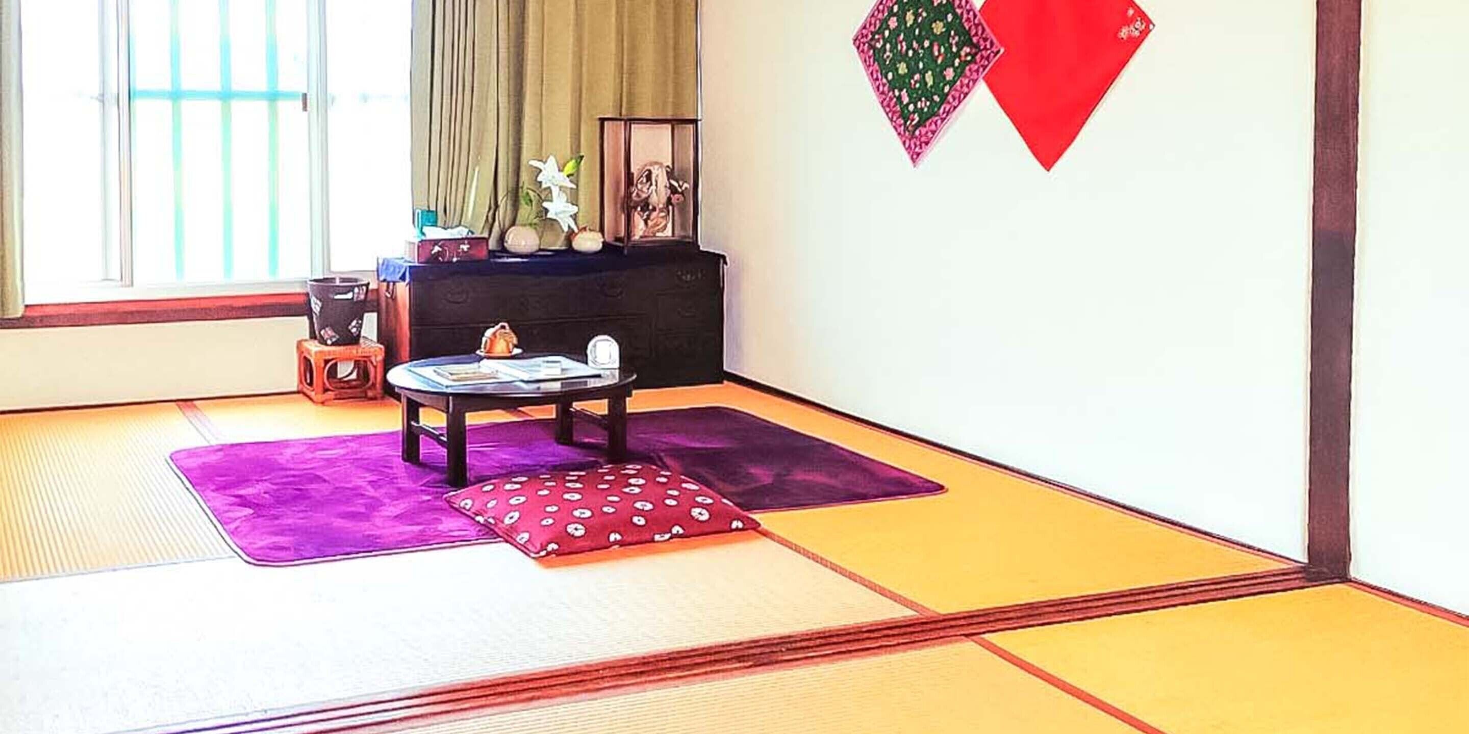 Um espaço com tatames, uma mesa baixa, almofadas e um pequeno armário.