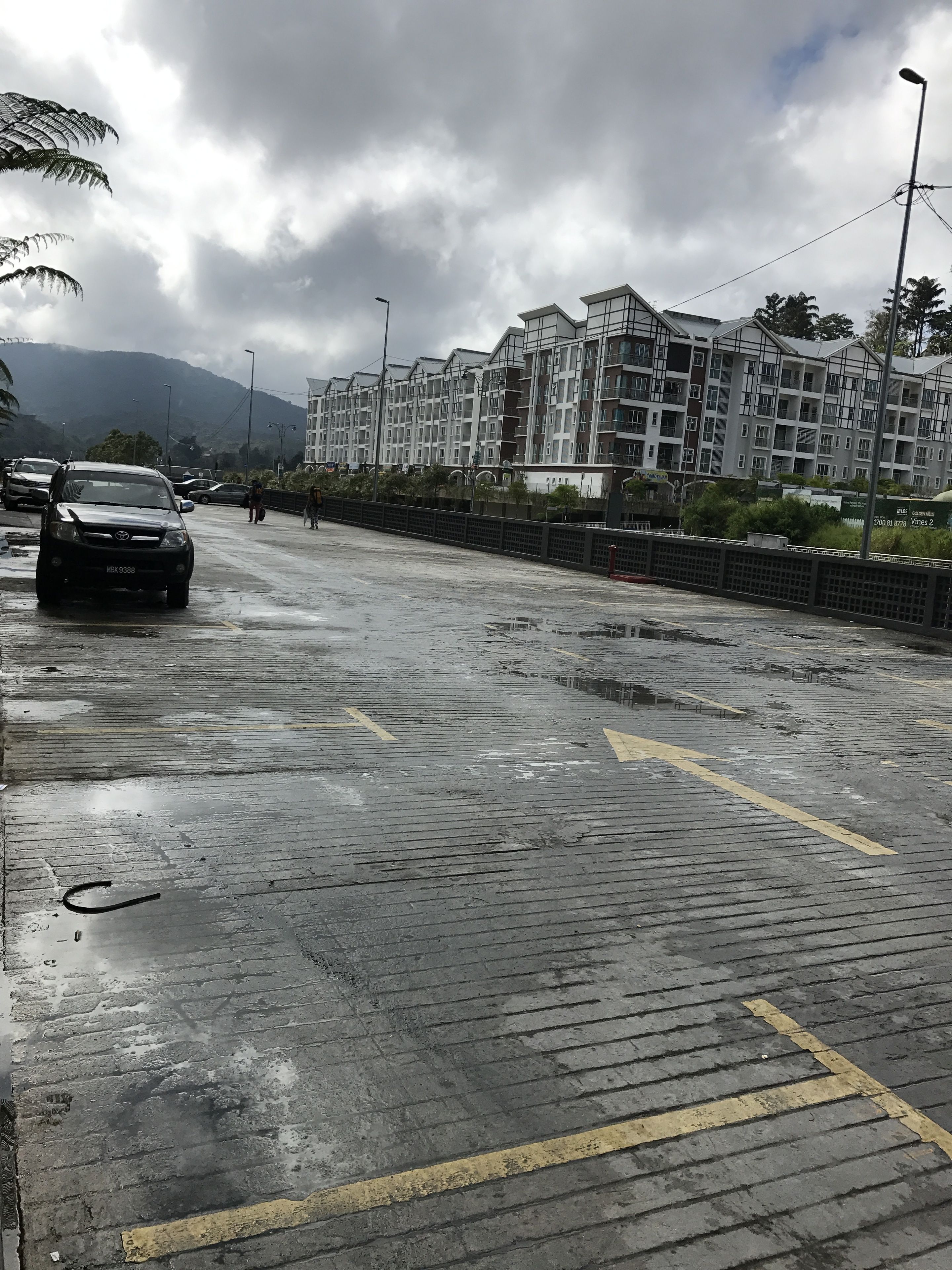 Uma rua molhada com um carro estacionado na lateral.