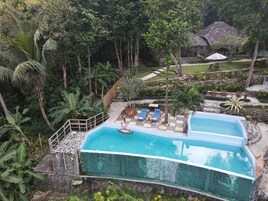 Piscina com espreguiçadeiras e um muro de pedra.