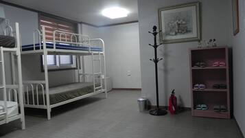 Quarto com beliche, um porta-roupas, um quadro emoldurado e um espaço para sapatos.