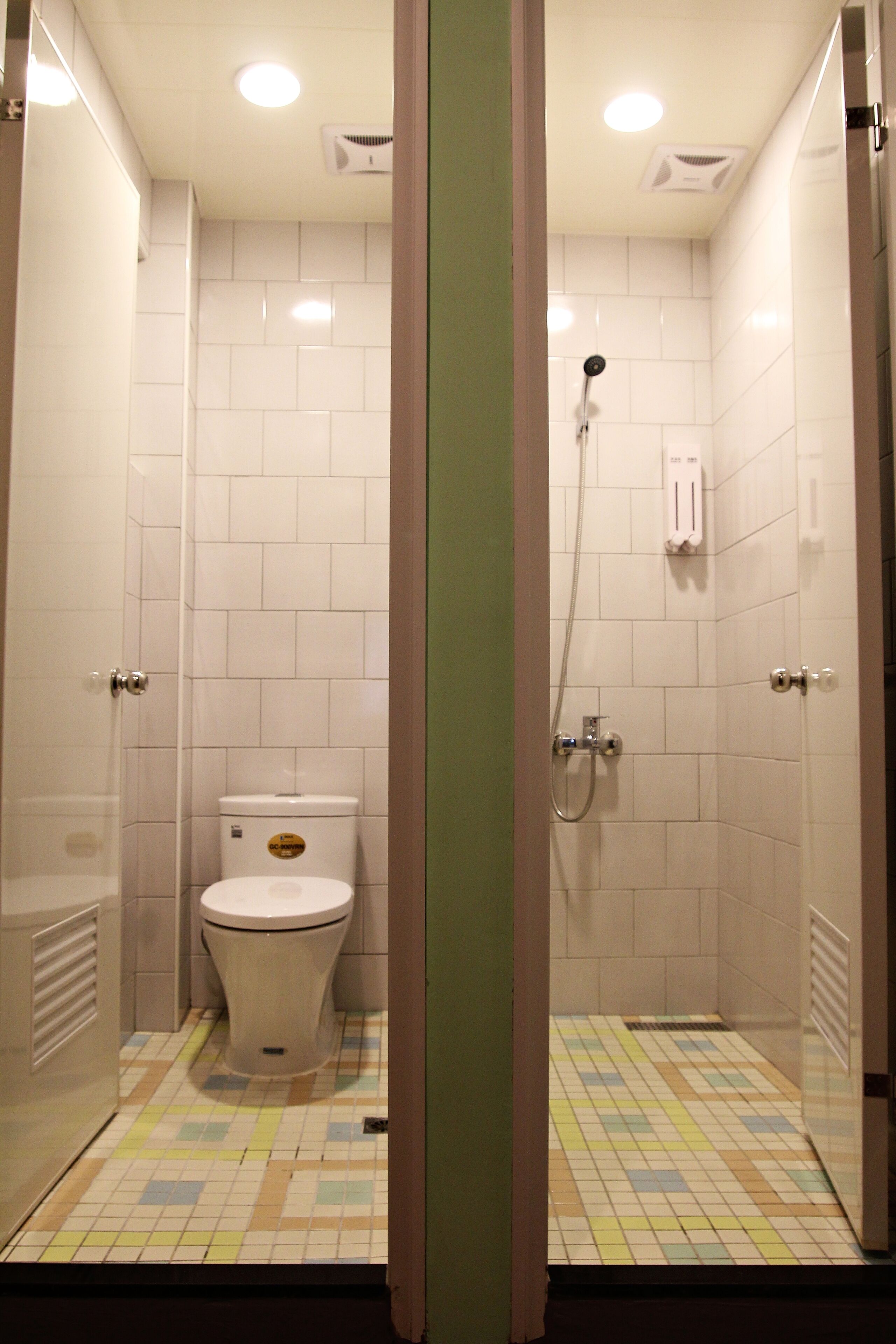 Um banheiro pequeno, com azulejos, incluindo vaso sanitário, chuveiro e piso revestido.