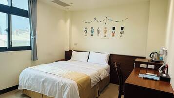Quarto de hotel com cama, escrivaninha de madeira, cadeira e um objeto decorativo na parede.