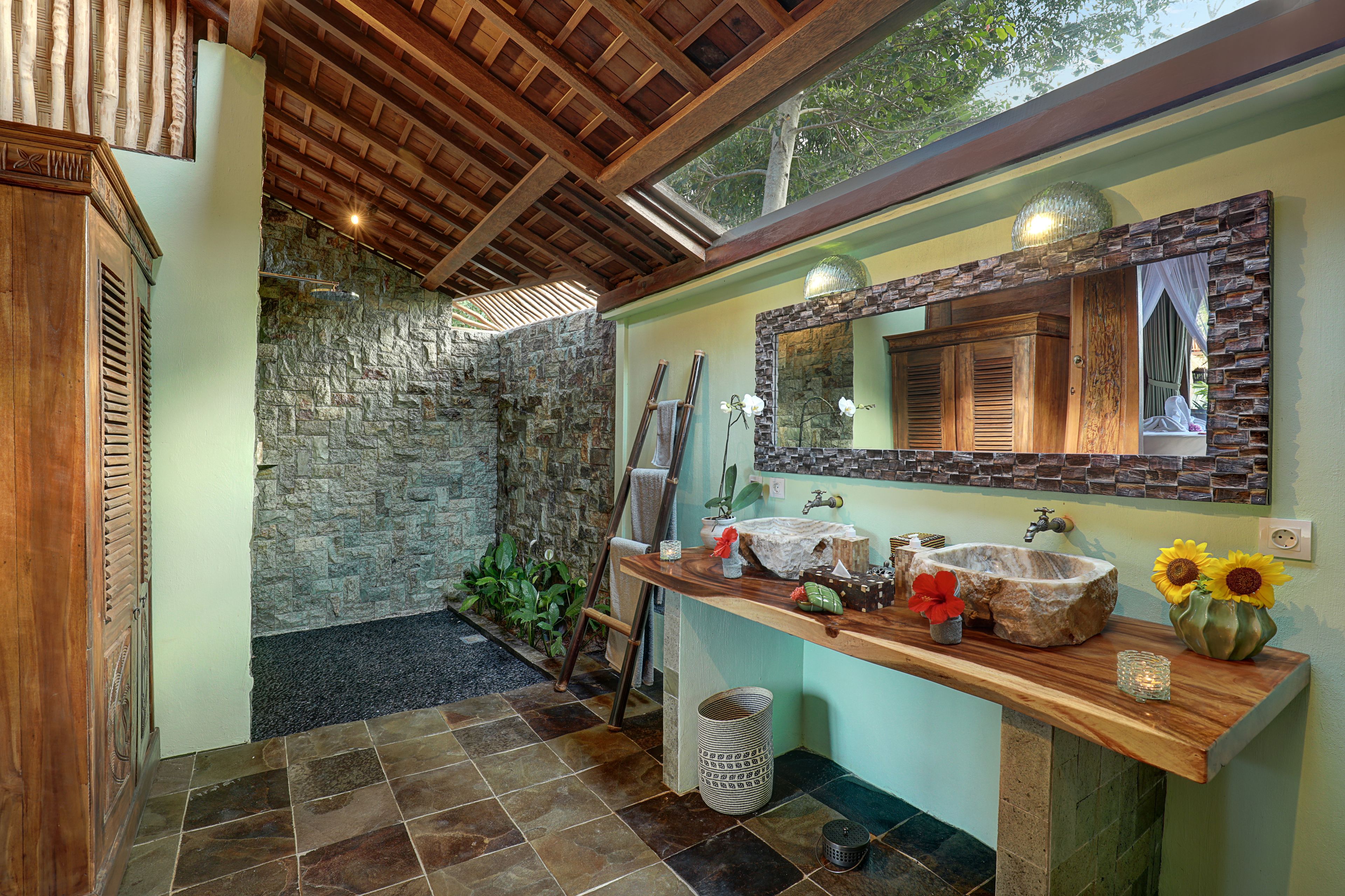 Casa de banho com parede de pedra, teto de madeira e toucador de madeira com lavatório e espelho.