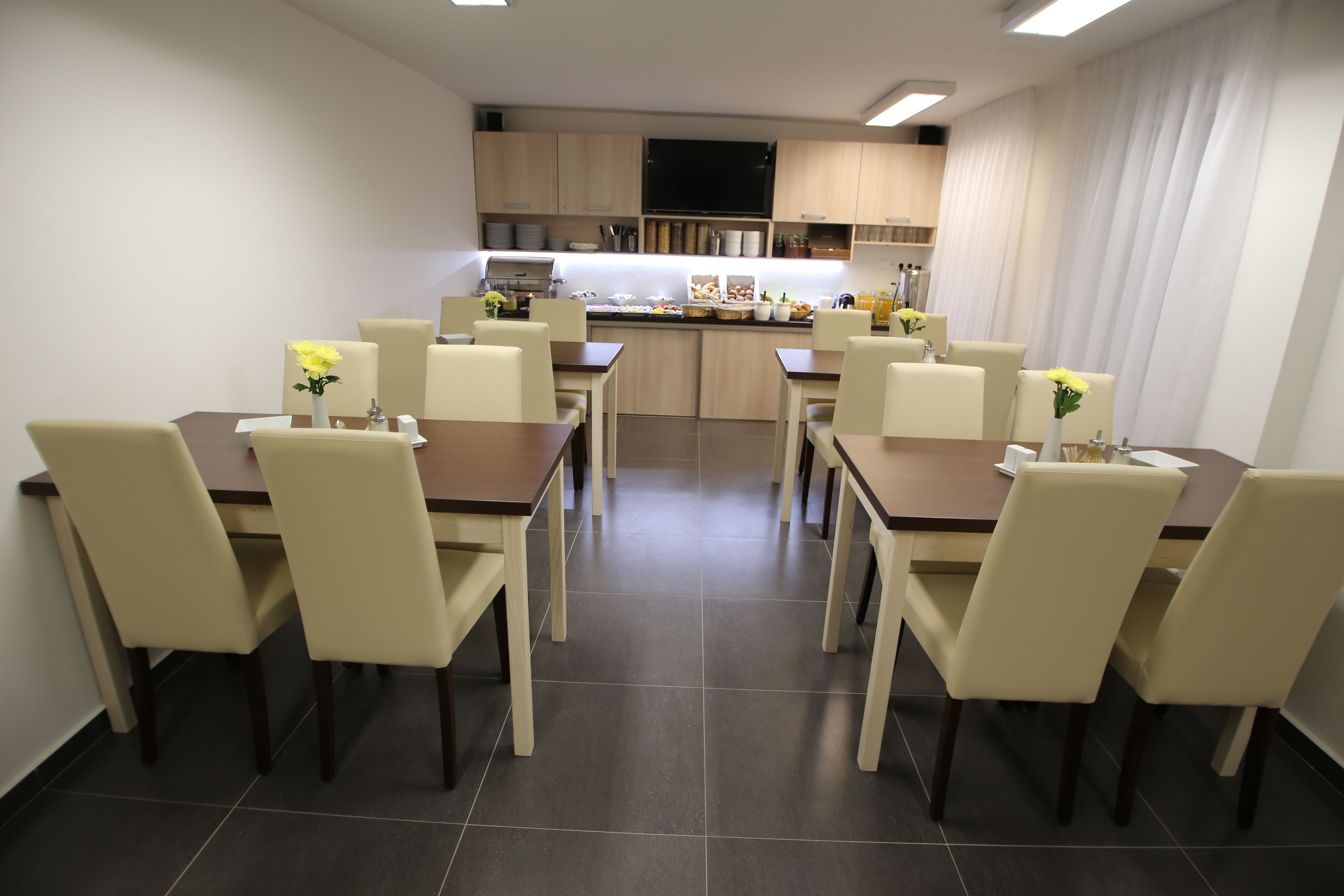 Uma área de refeições com uma ilha central, cadeiras e uma cozinha ao fundo.