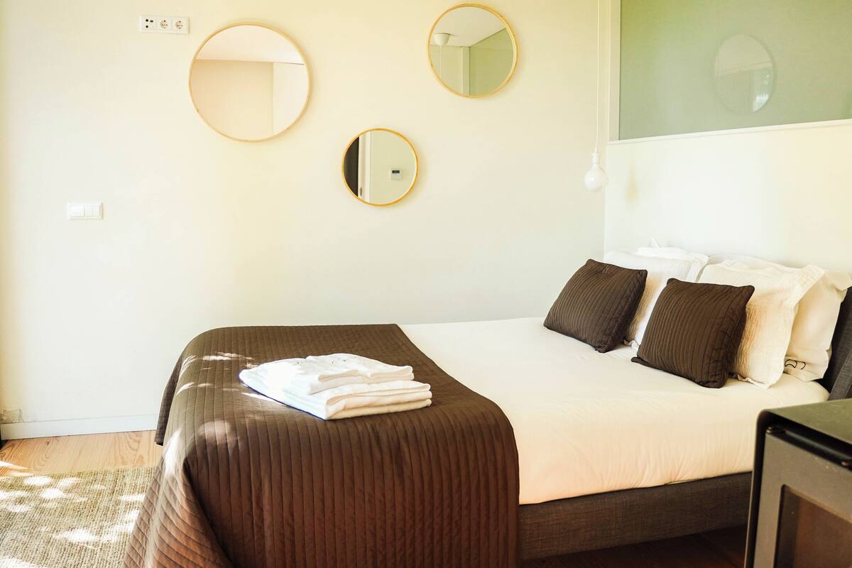 Quarto de hotel com cama, almofadas, espelho e televisão.