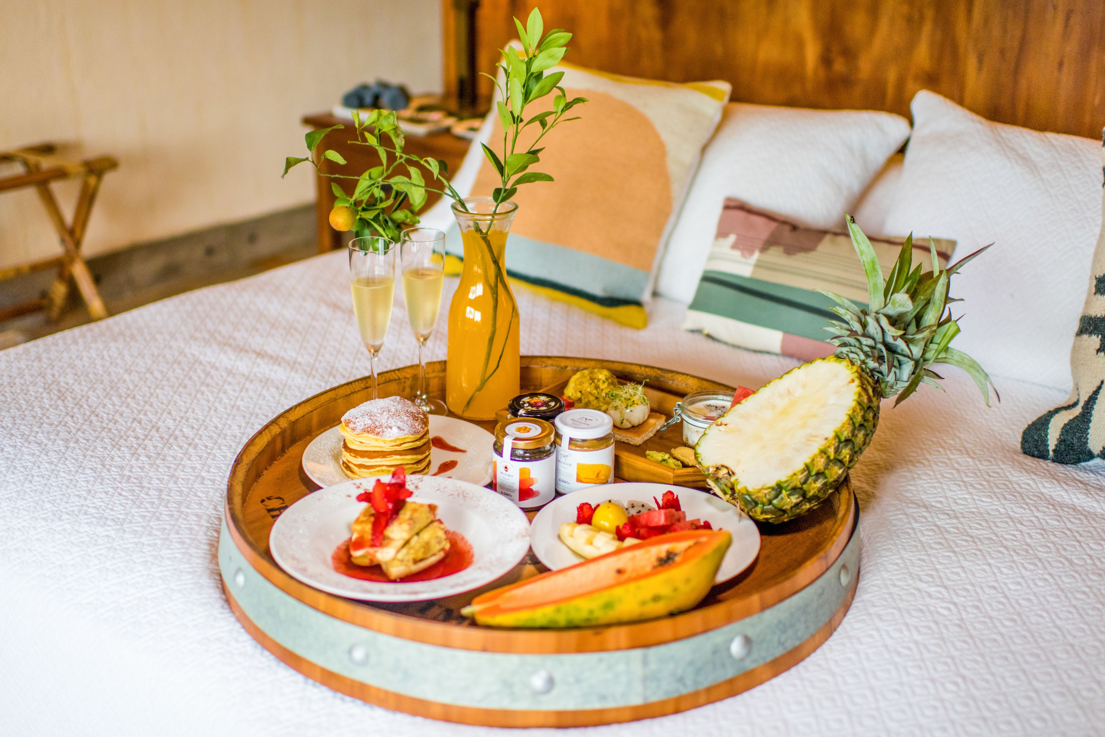 Bandeja de café da manhã com diversos alimentos e bebidas sobre a cama.