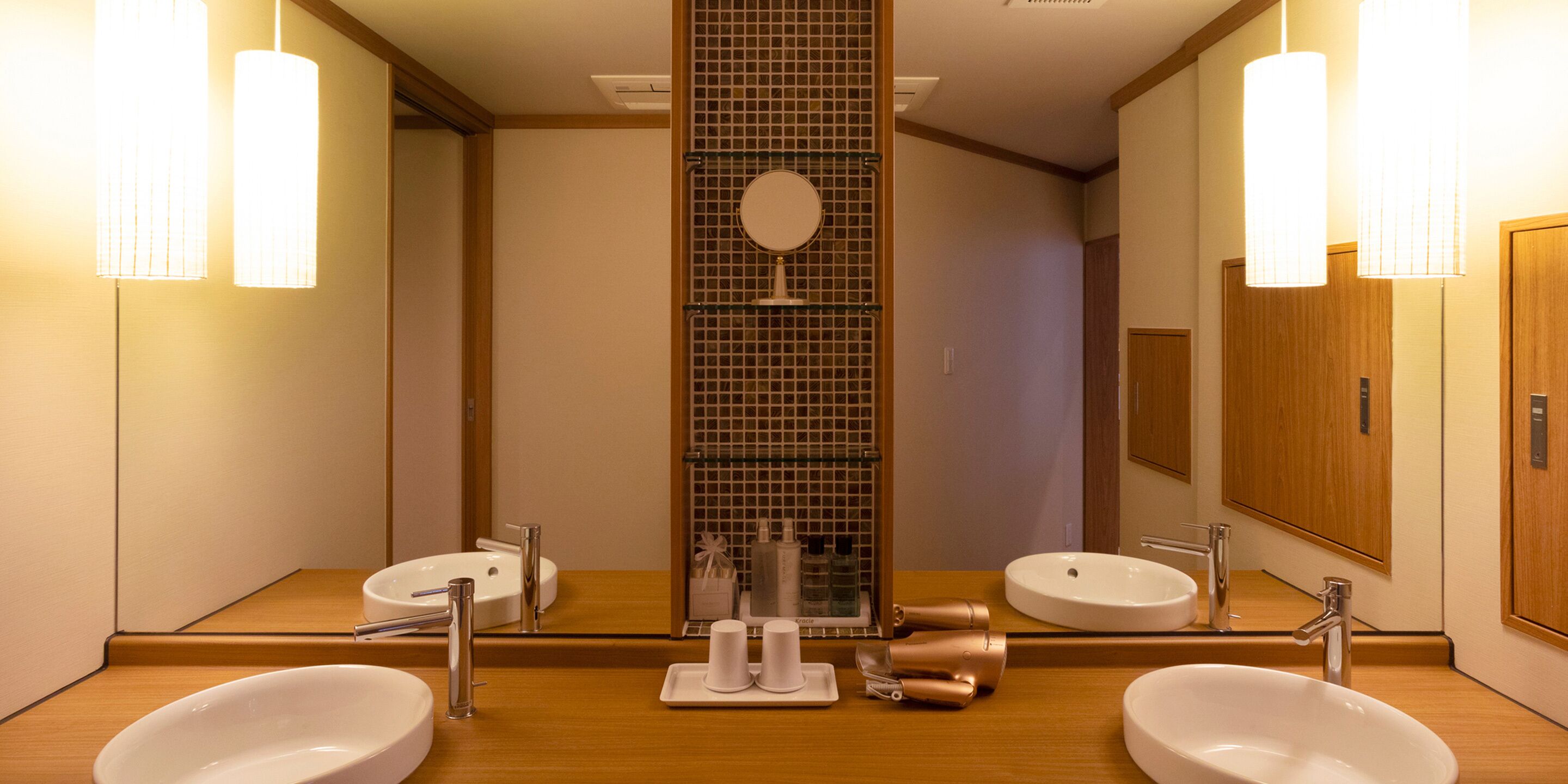 Casa de banho de hotel com duas pias, um espelho grande e um porta-toalhas.