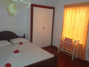 Um quarto com uma cama, um guarda-roupa, uma cadeira e uma janela com cortinas.