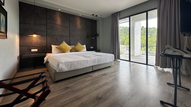 Quarto moderno com uma cama grande, uma escrivaninha e vista para o verde pela janela.