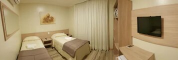 Quarto de hotel com duas camas, uma mesa de escritório, televisão e janela com cortinas.