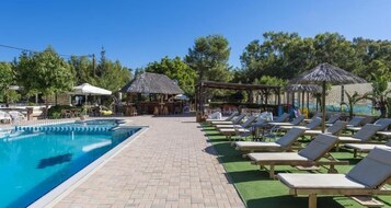 Piscina com espreguiçadeiras e área de bar.