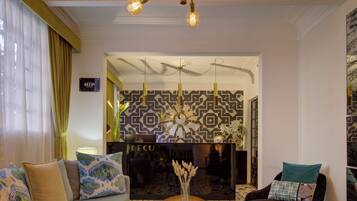 Uma sala de estar moderna com um piso estampado em padrão geométrico, um sofá, uma poltrona, uma mesa de centro redonda de madeira e um lustre de teto exclusivo.