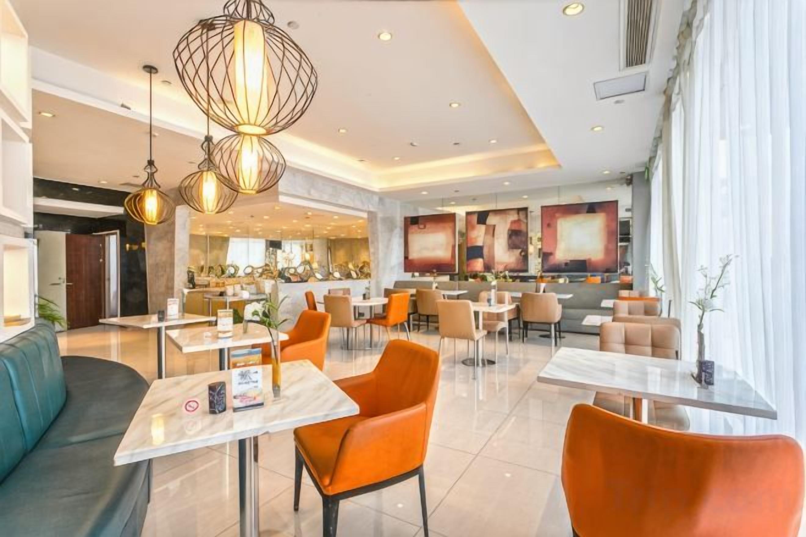 Um lobby de hotel moderno com área de bar, assentos e uma grande janela que oferece luz natural.