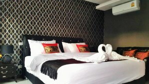 Quarto de hotel com cama, almofadas, mesa de cabeceira e parede com padrão geométrico.