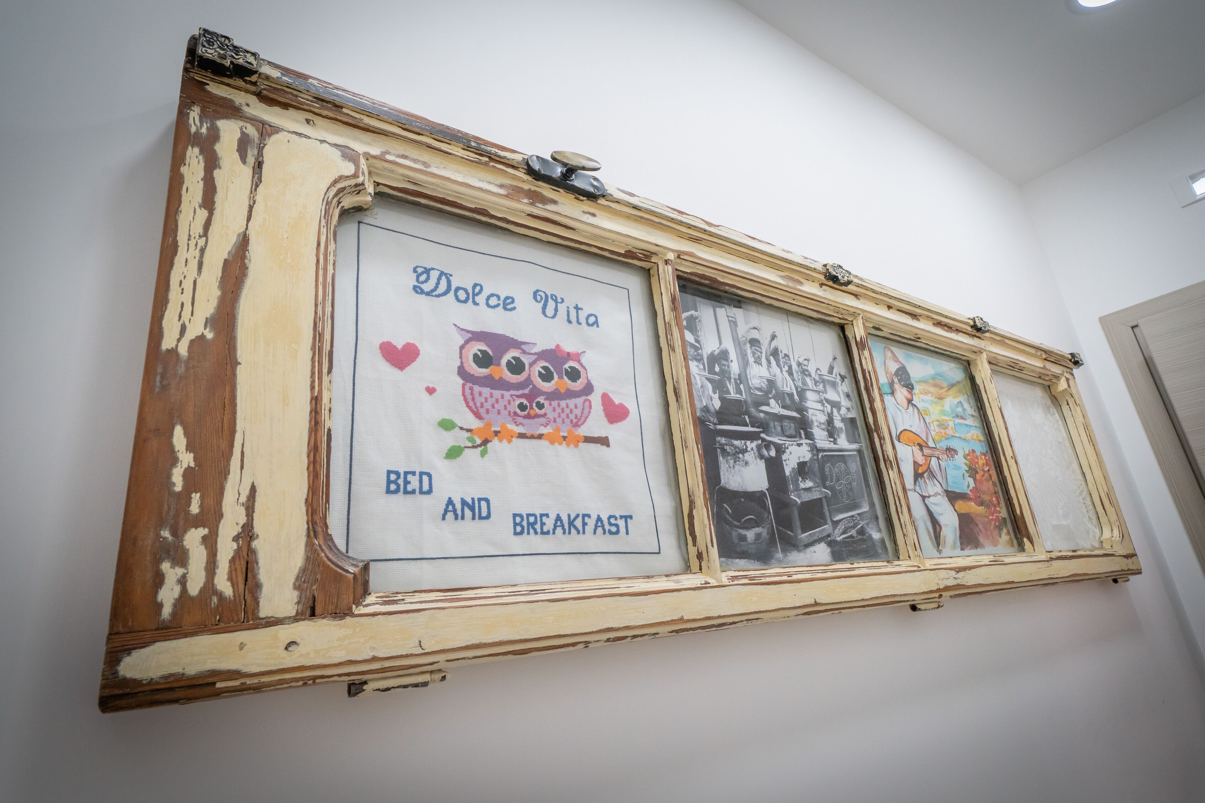 Paredes com moldura rústica e desgastada exibindo uma ilustração colorida de uma coruja e o texto "Dolce Vita Bed and Breakfast".