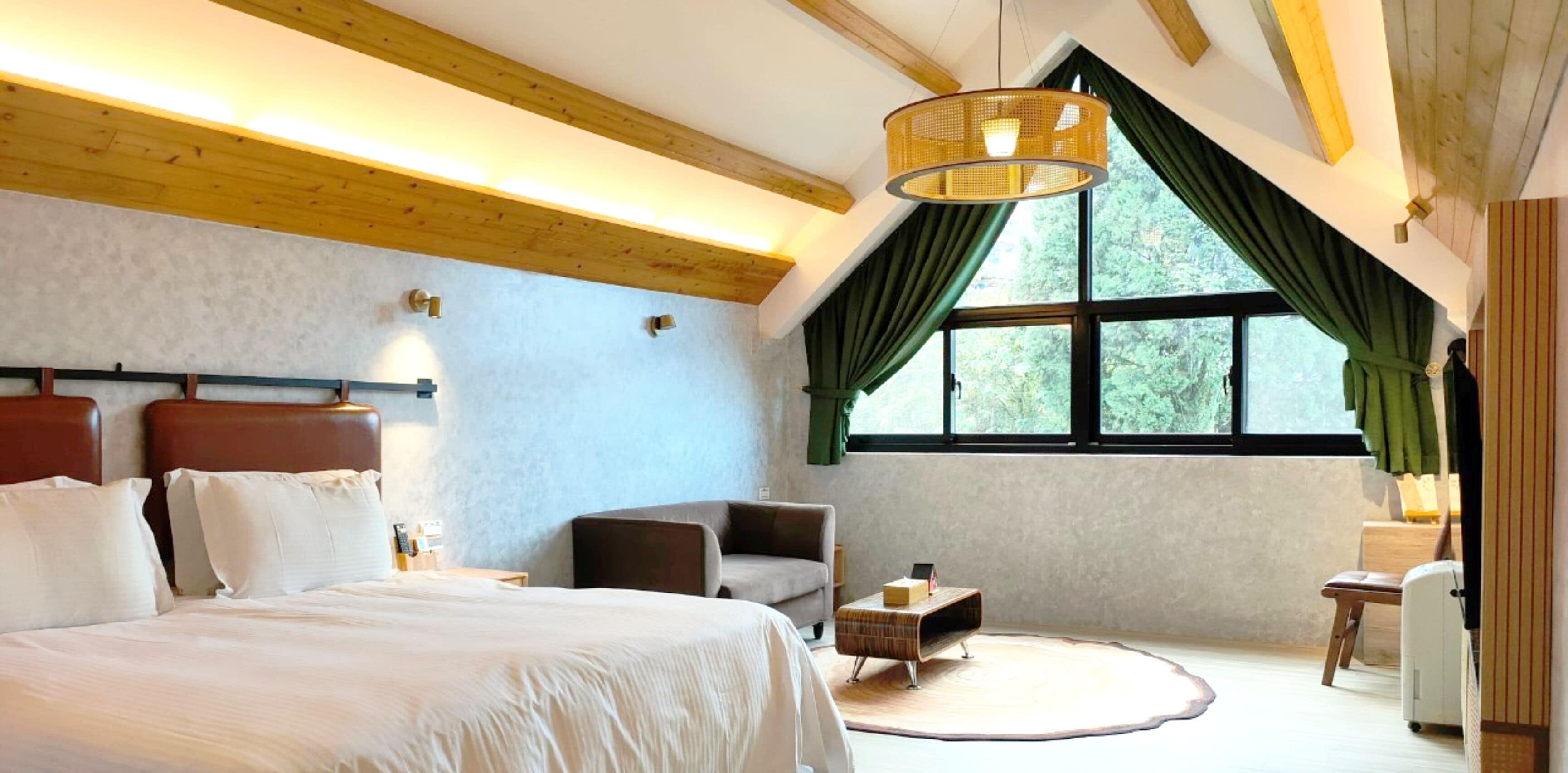 Quarto com uma cama grande, teto de madeira, janela com cortinas e uma mesa pequena.