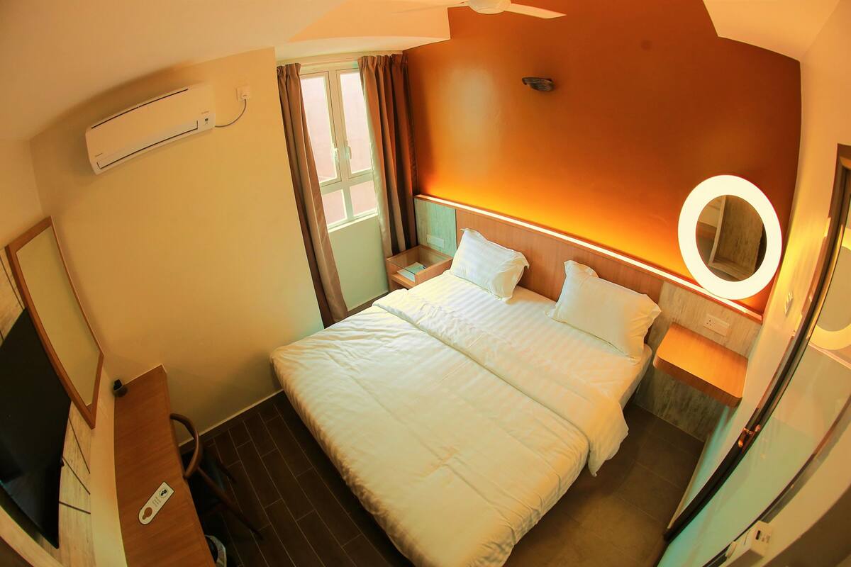 Quarto de hotel com cama, mesa de cabeceira, espelho e ar condicionado.