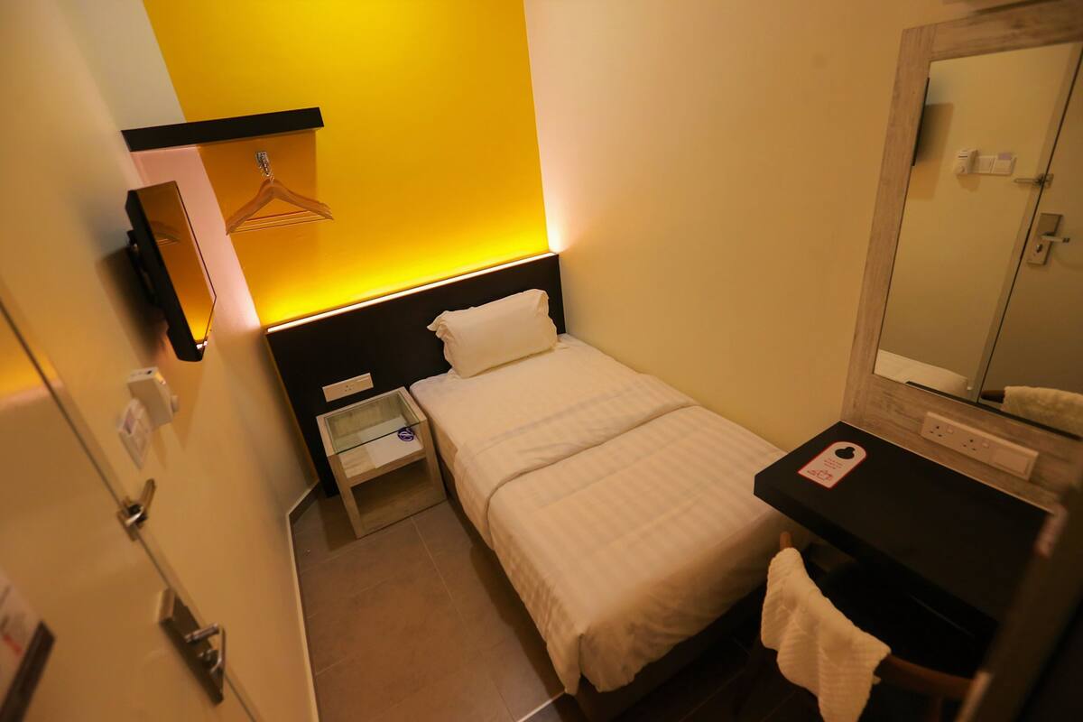 Quarto de hotel com cama, mesa de cabeceira e espelho.