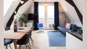 Um loft moderno com área de refeições, sofá, televisão e cozinha.
