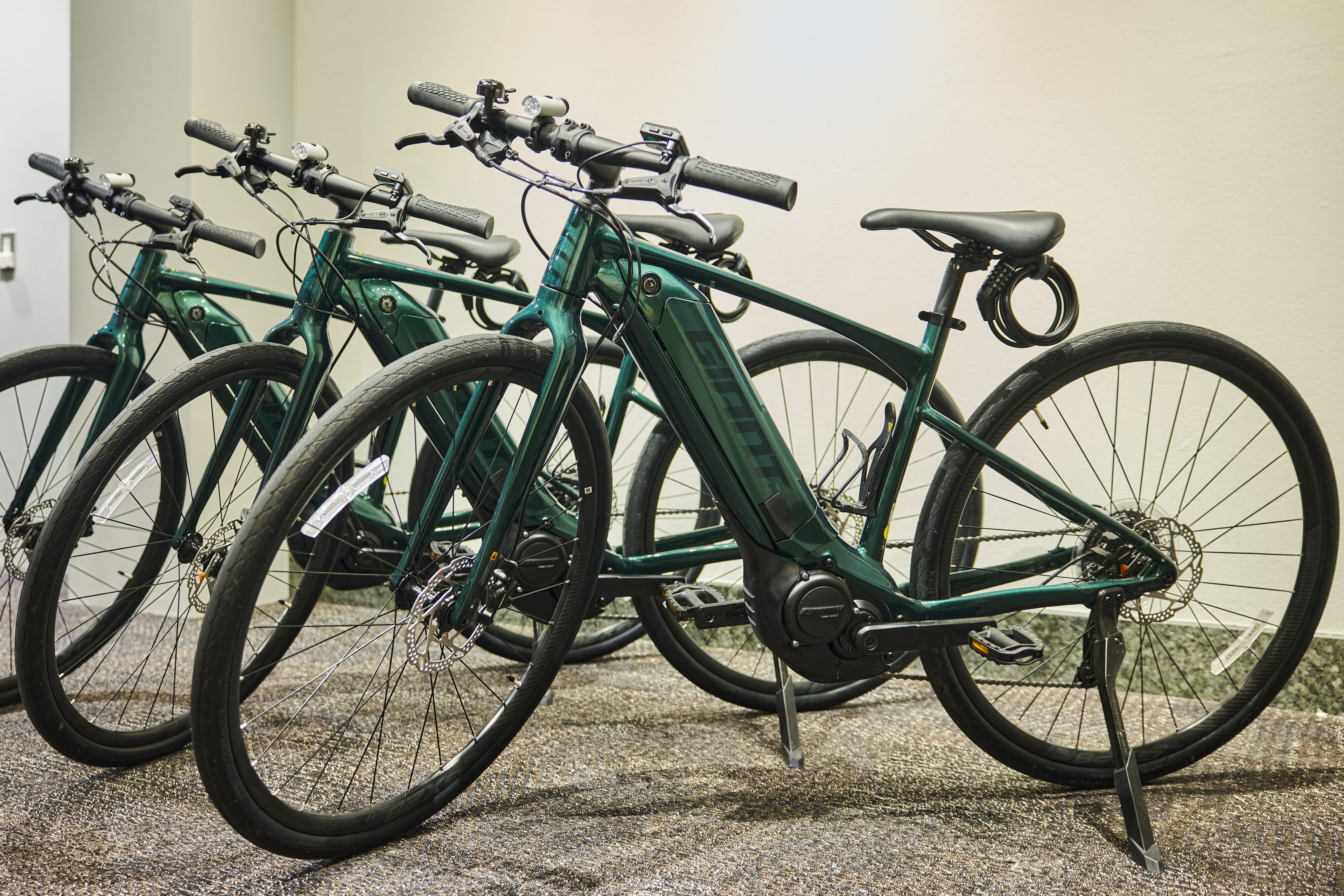 Uma fileira de bicicletas ergométricas com cadeado, guidão e pedais.