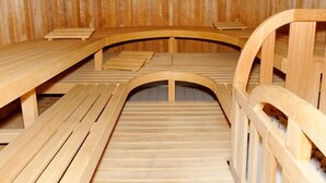 Uma sauna com bancos de madeira, teto curvo e paredes de madeira.