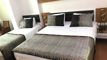 Quarto de hotel com duas camas, cabeceira de madeira, telefone e quadro fixado na parede.