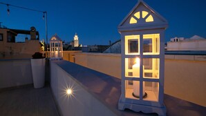 Terraço no telhado com luminária branca em estilo de lanterna e lixeira branca.