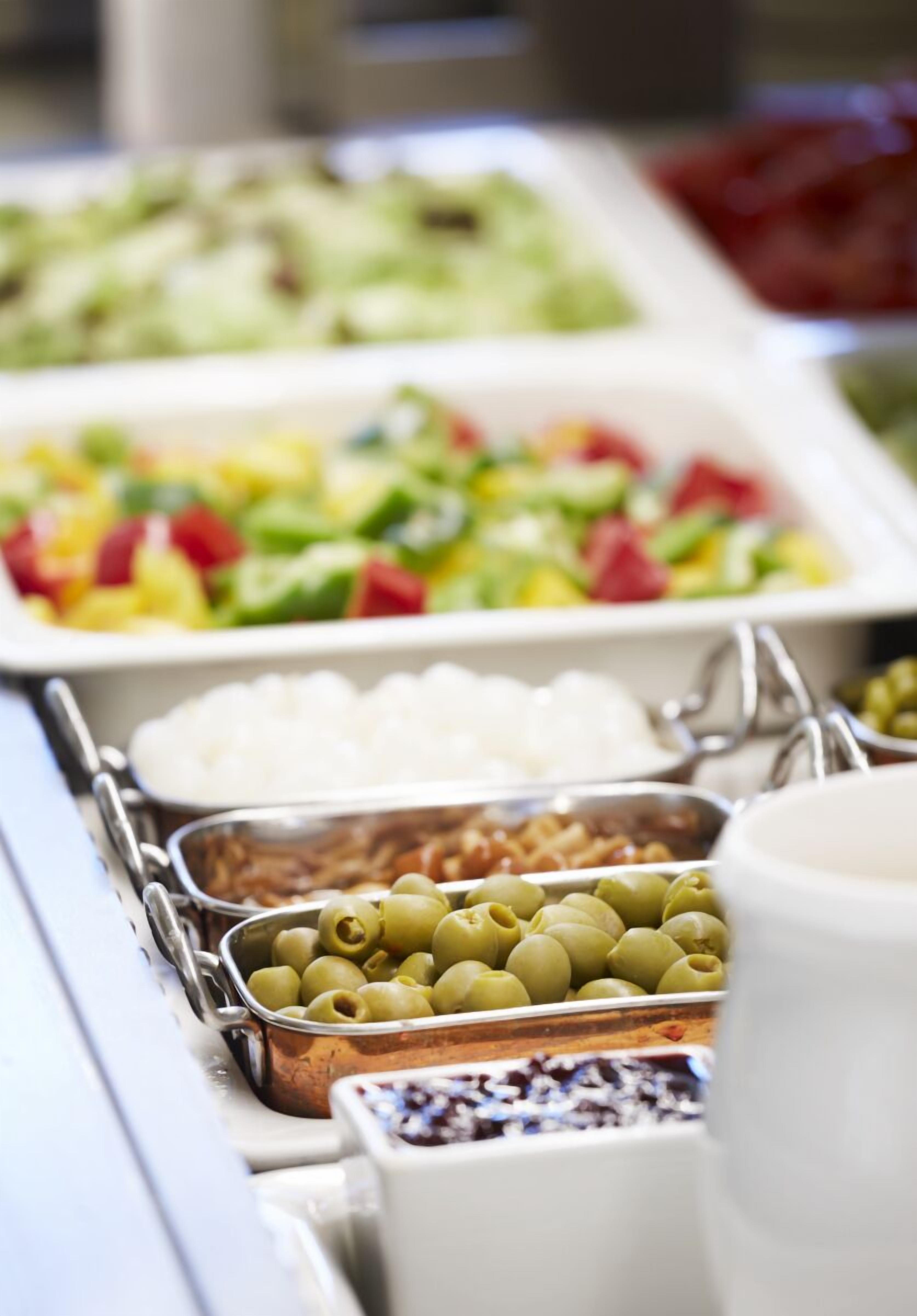 Buffet com diversas opções de comida, incluindo saladas, arroz e azeitonas.