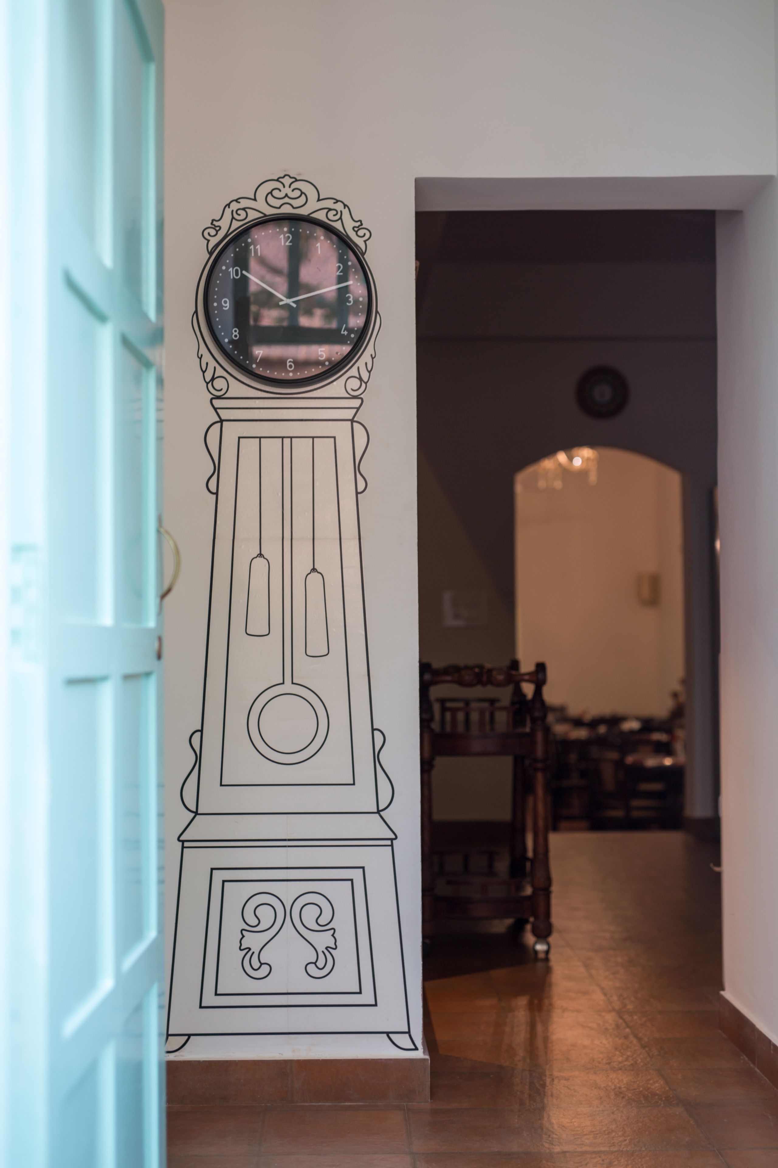 Um corredor com um relógio de chão grande e ricamente decorado fixado na parede.