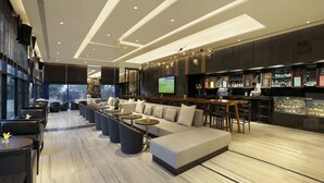 Uma área de bar moderna com sofá, mesas e uma tela de televisão.