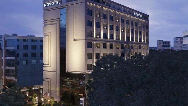 Um edifício de hotel moderno com o nome 'NOVOTEL' em destaque.
