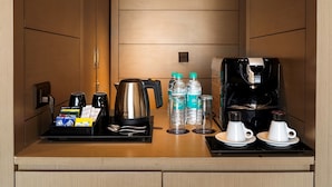 Uma cozinha compacta equipada com cafeteira, garrafas de água e chaleira.