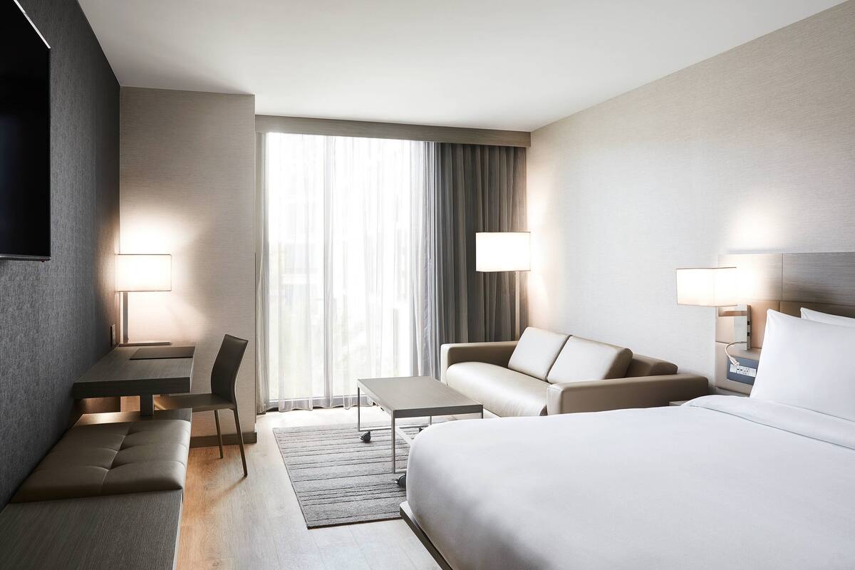Quarto de hotel moderno com cama, sofá, escrivaninha e cadeira.