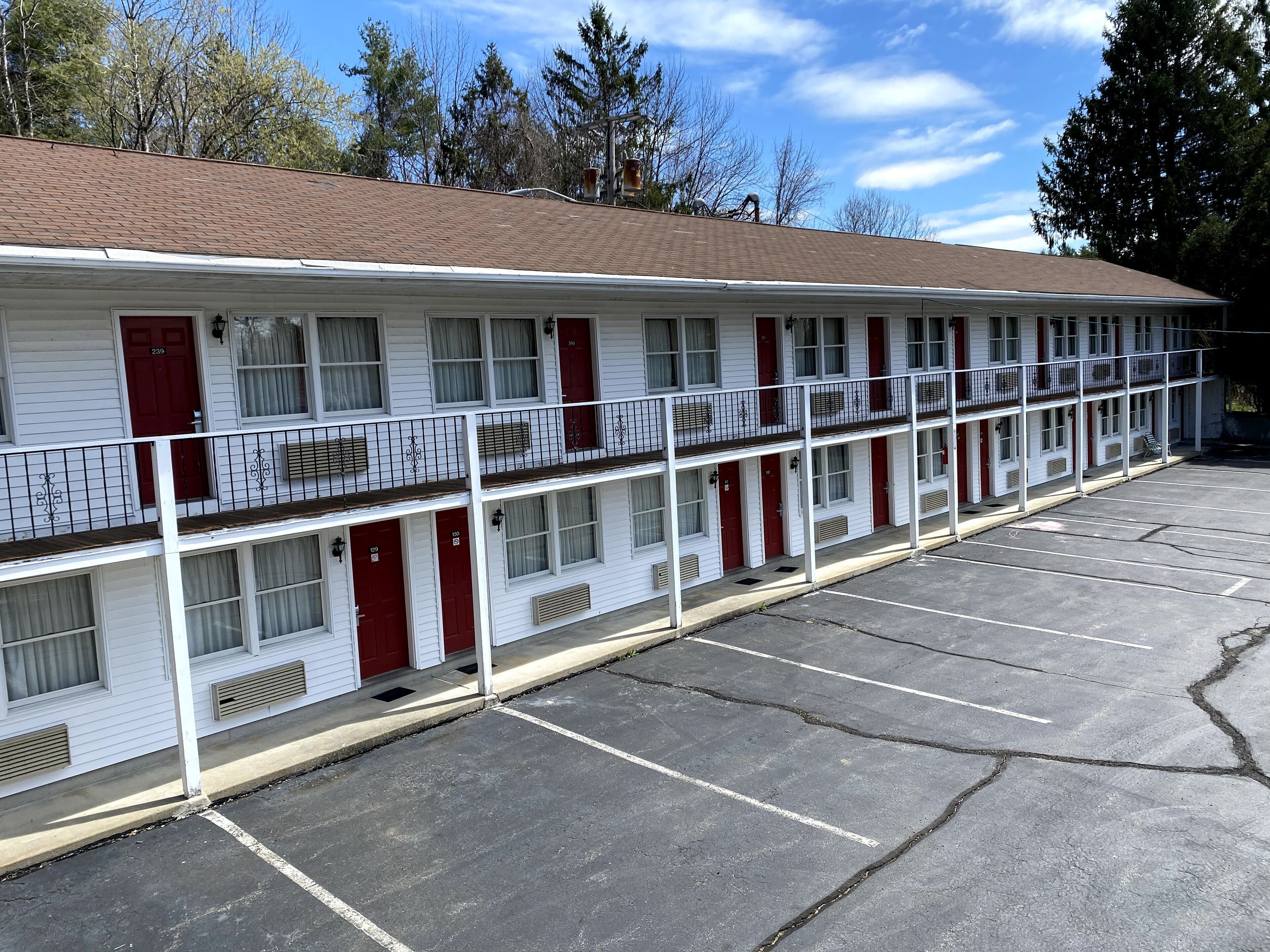 Um motel com uma fileira de quartos, cada um com uma porta vermelha e uma varanda.