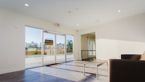 Um hall amplo com design moderno, incluindo uma mesa de recepção, área de estar e grandes portas de vidro que dão para o exterior.