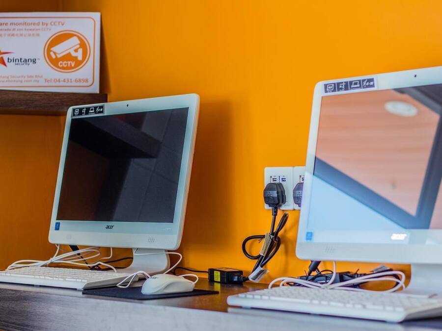 Dois monitores Acer numa mesa com um aviso a indicar vigilância por circuito fechado.