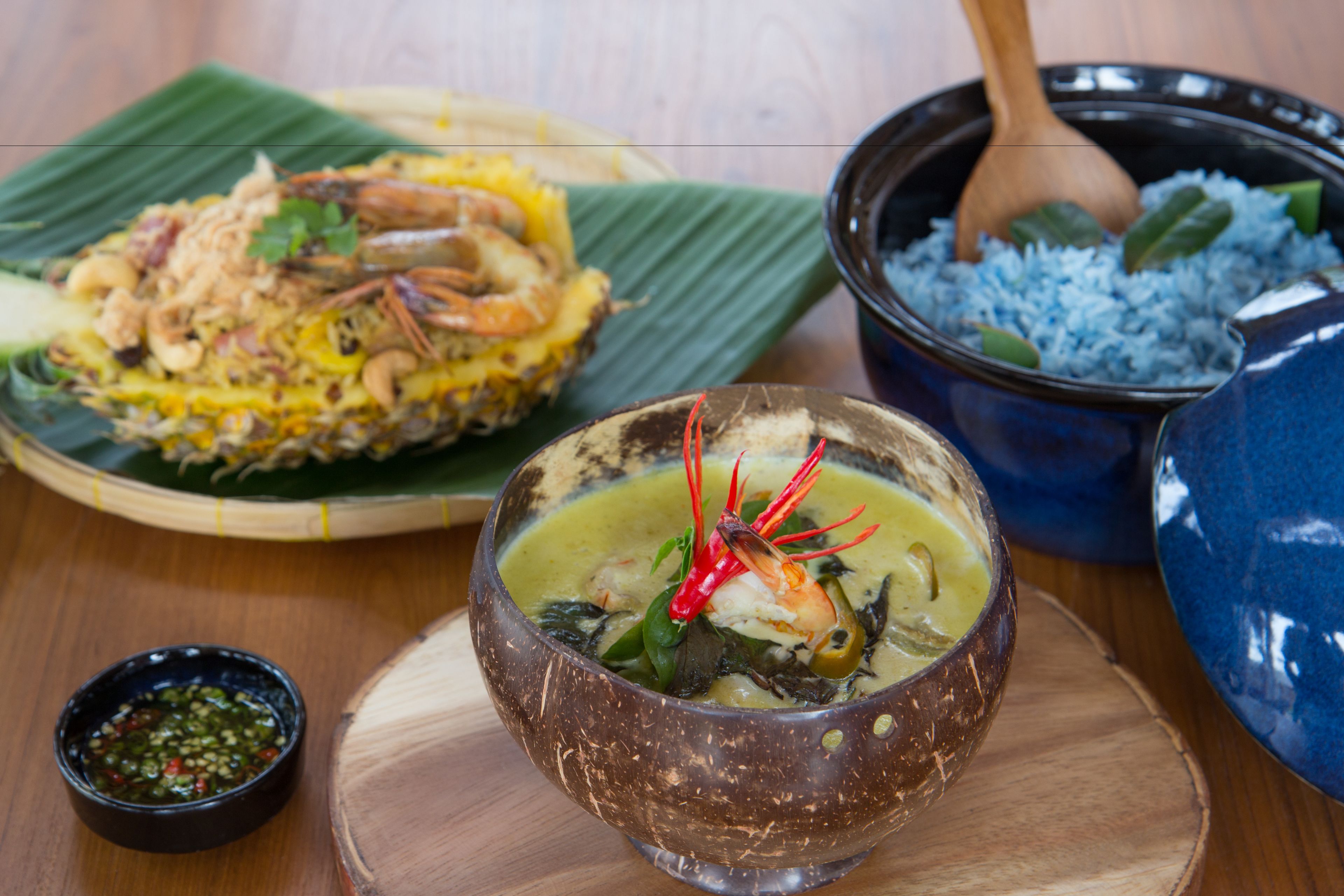 Uma mesa com uma tigela de sopa, um prato de comida e uma tigela de arroz.