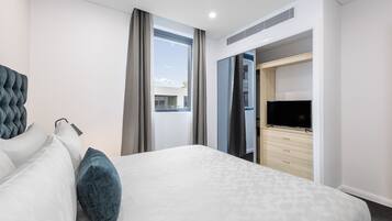 Quarto de hotel moderno com uma cama grande, televisão e vista para a cidade.