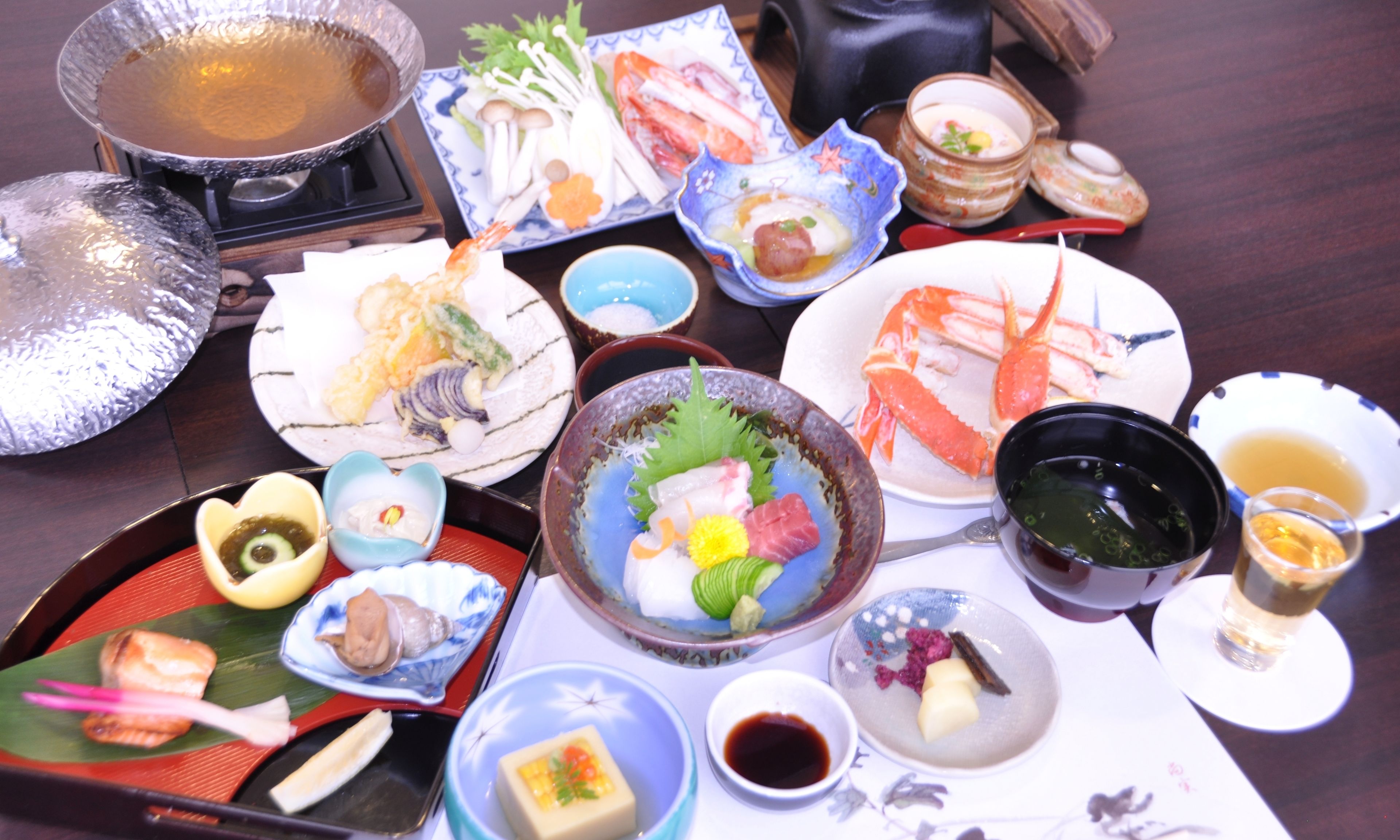 Diversos pratos da culinária japonesa em uma mesa, incluindo frutos do mar, legumes e arroz.