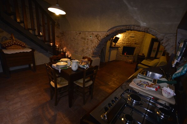 Cozinha rústica com forno de pedra, mesa de jantar de madeira e cadeiras.