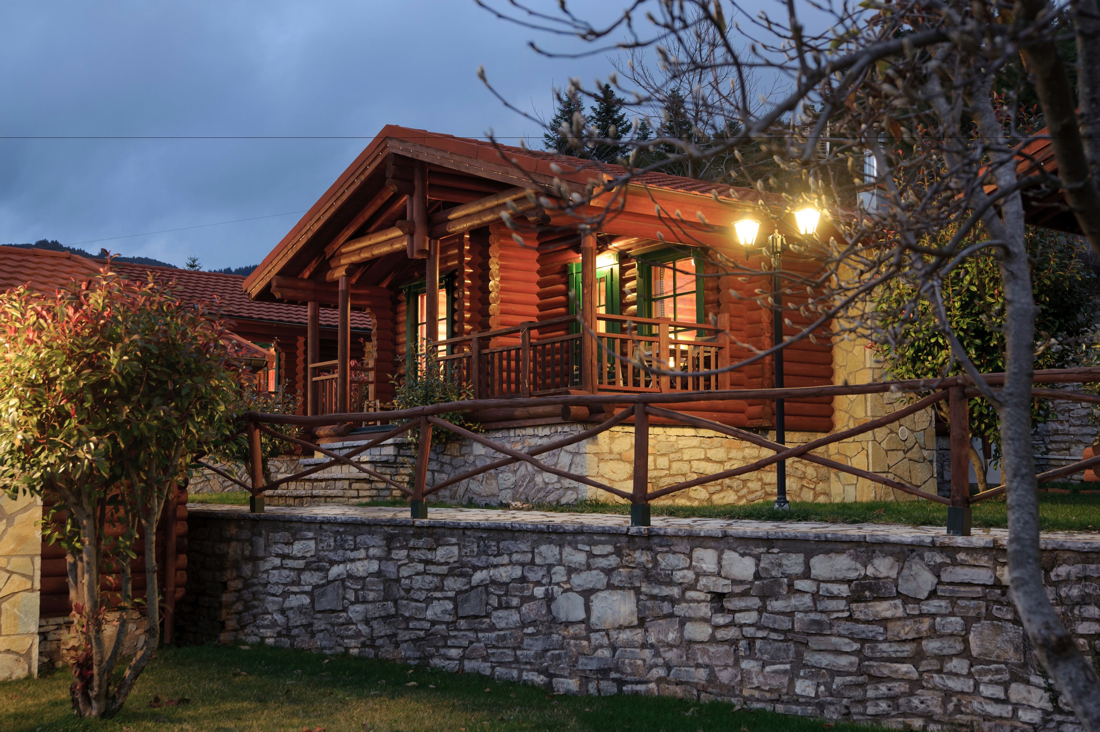 Uma cabana de toras com base de pedra, deck de madeira e varanda com corrimão.