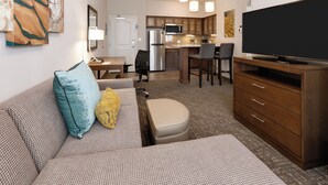 Um espaço compacto com cozinha compacta, área de refeições e sala de estar com sofá e apoio para os pés.