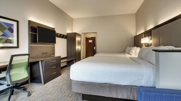 Quarto de hotel com cama, escrivaninha, cadeira, televisão e porta.
