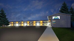 Um Days Inn by Wyndham com um amplo estacionamento e fachada bem iluminada.