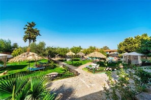 Um resort com cabanas de telhado de palha, piscina e um jardim bem cuidado.