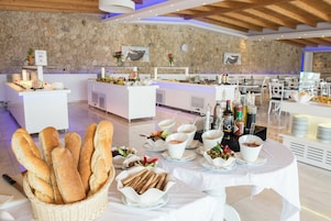 Mesa de buffet com pães, molhos e acompanhamentos.